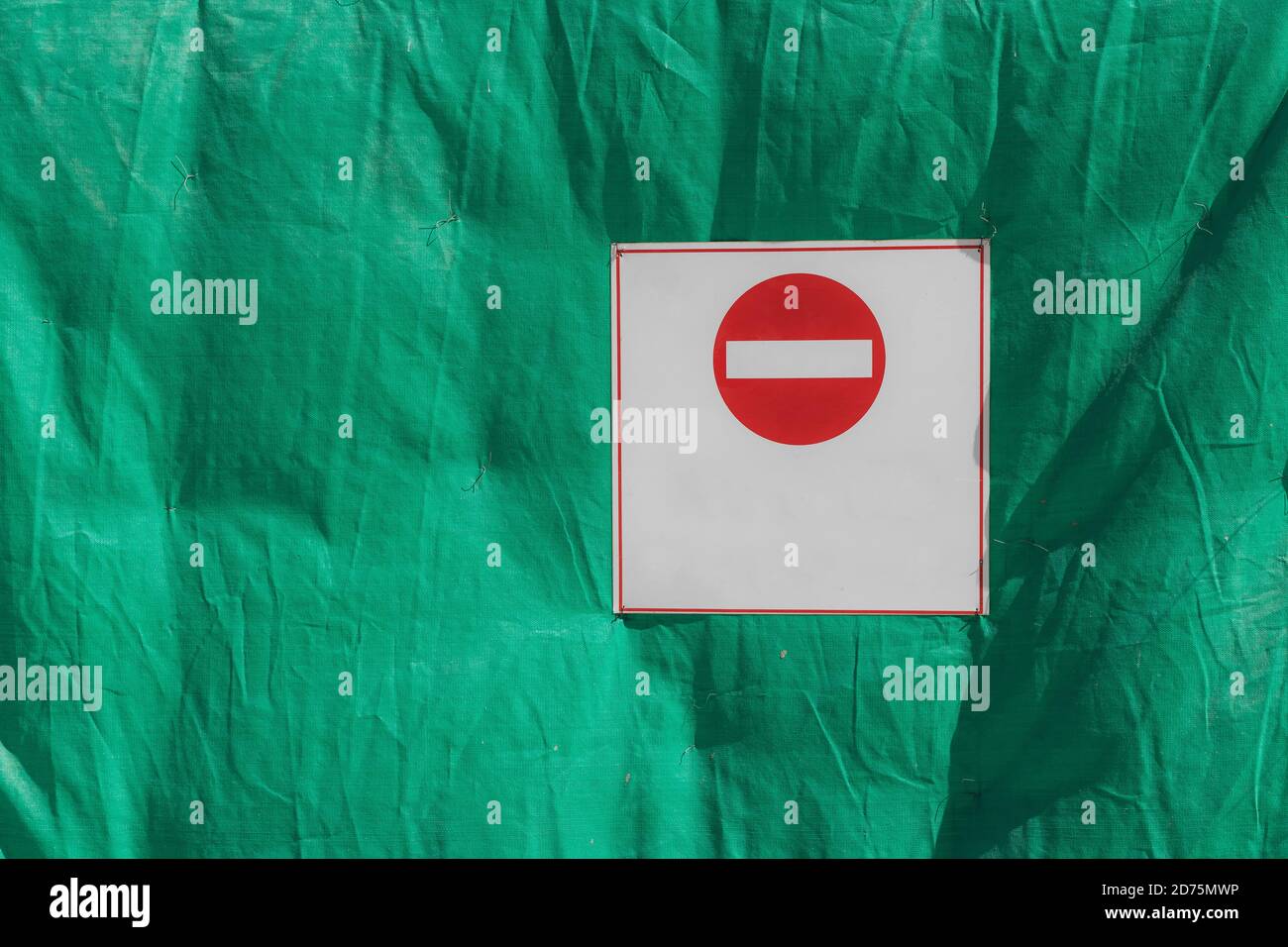 Round red and white "Do not enter" stop sign on a plate against a green ...
