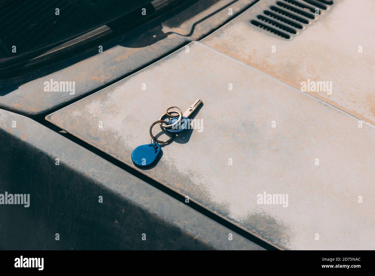 Lonely bunch of blue magnet keys on dirty old and rusting car, on the ...