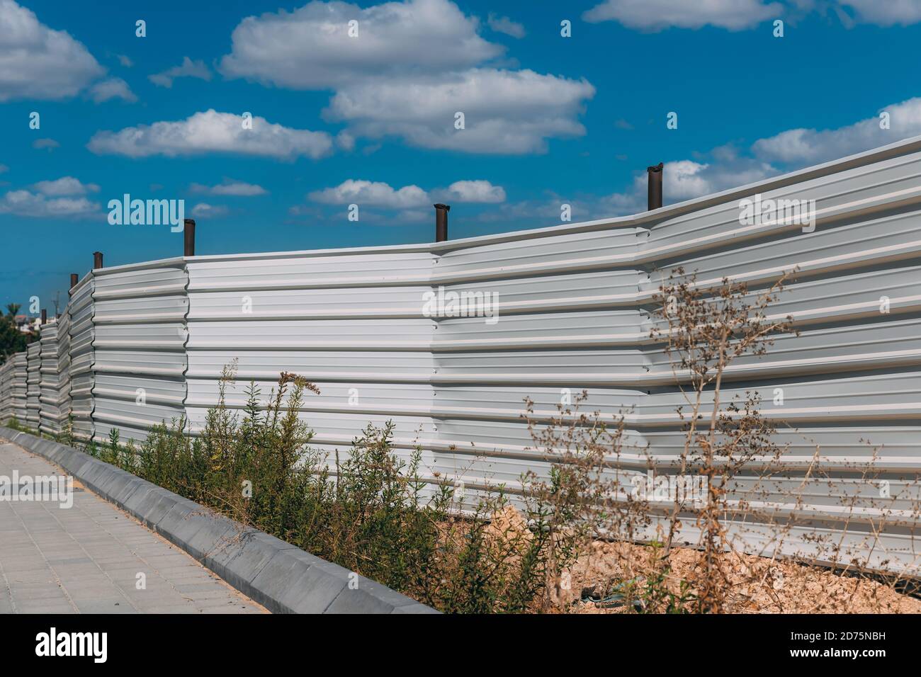 A light-colored construction site fence with stripes on a city street ...