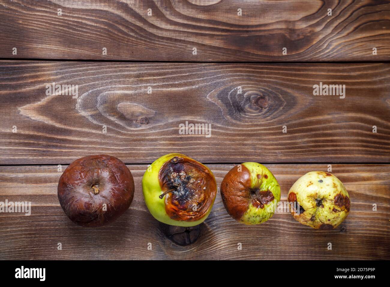 Rotten and moldy apples on a wooden background. Flat layout. Copy space ...