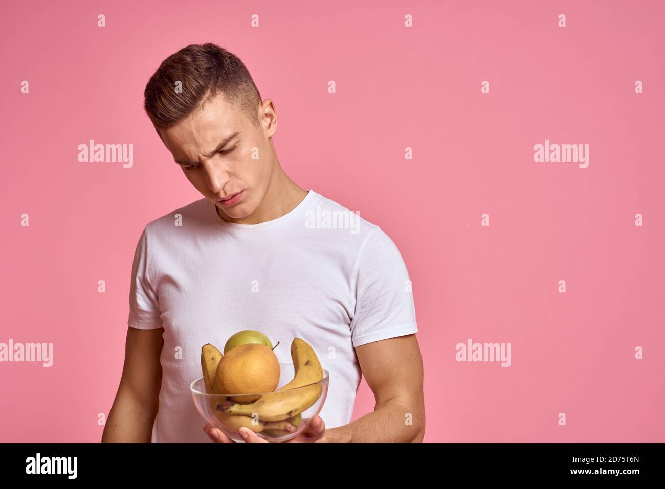 Man with fruits in hands on a pink background healthy food vitamins ...