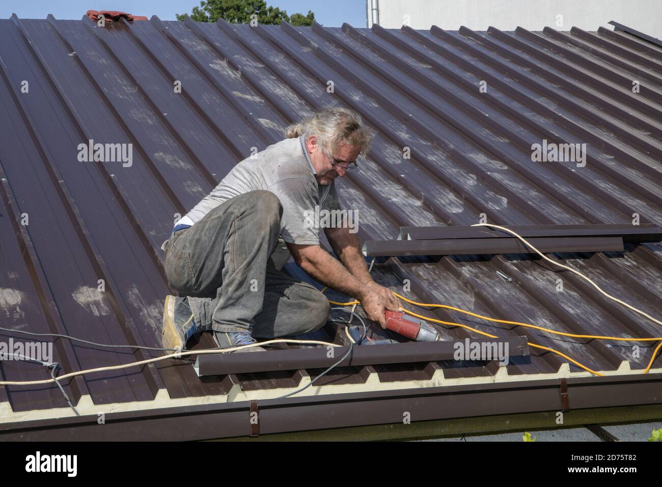 Repairing the roof of the house with screws drive tools. Worker roofer ...