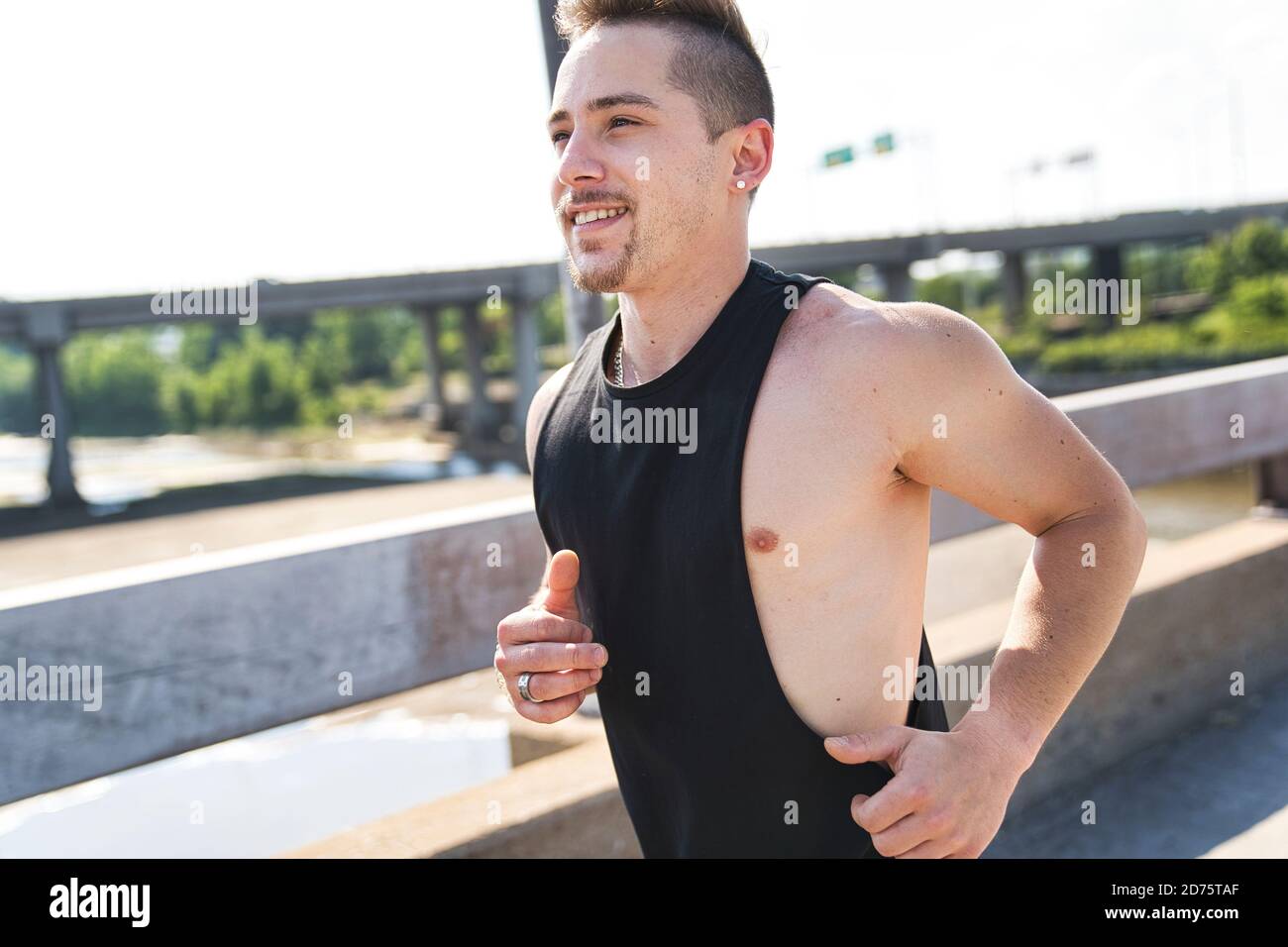 portrait of an athletic young man running and working out in the city ...