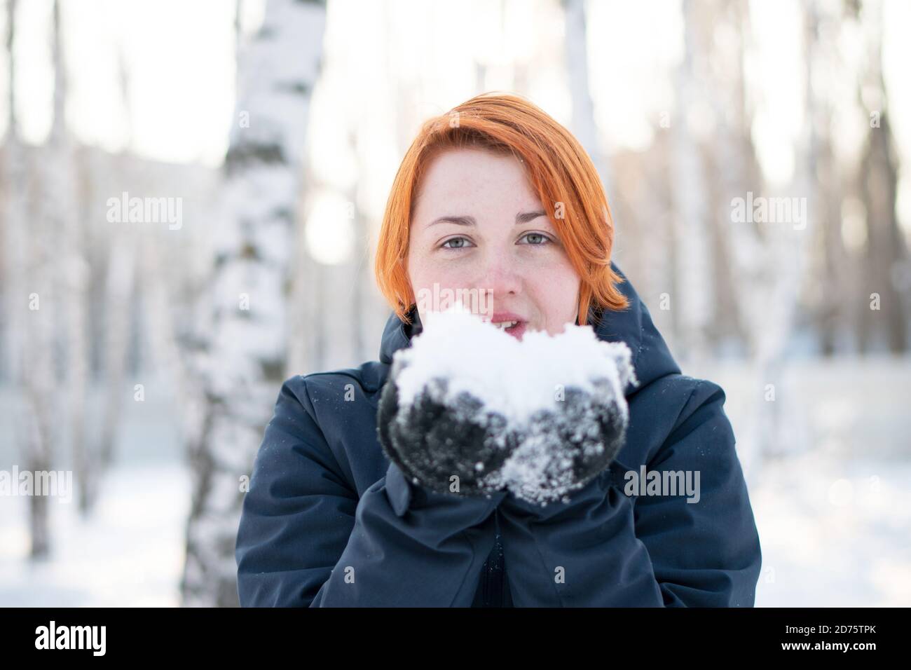 Girl with nordic appearance want to blow at snow in her hands. Winter ...