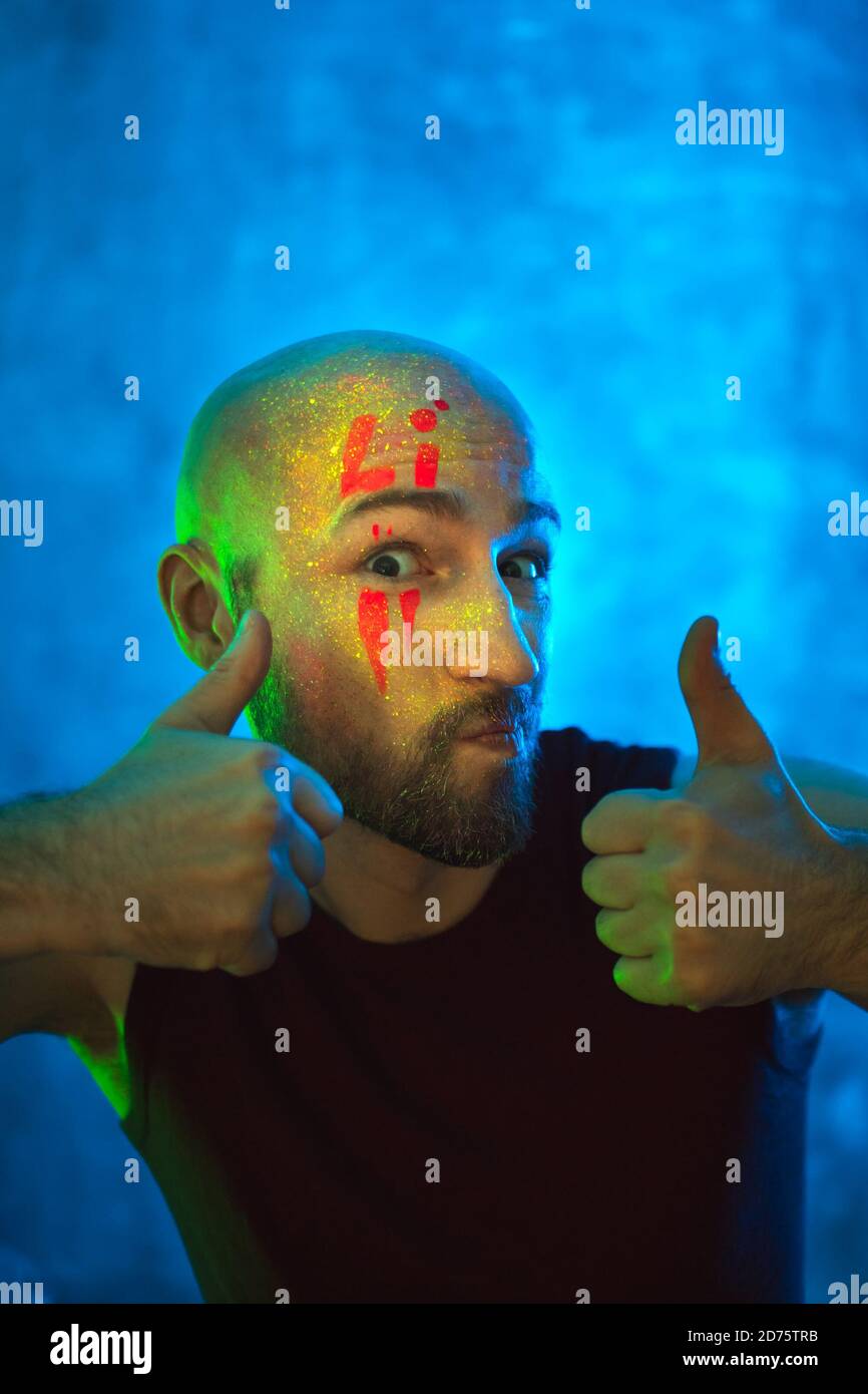 Stylish bald man with drawing face shows thumbs up. Fluorescent paint ...