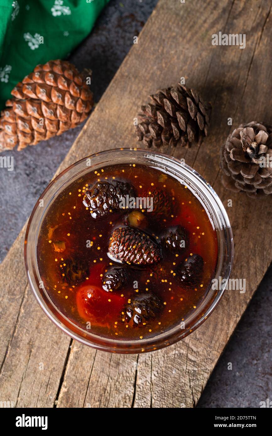 Young pine cones jam in glass bowl on wooden board. Delicious jam with ...