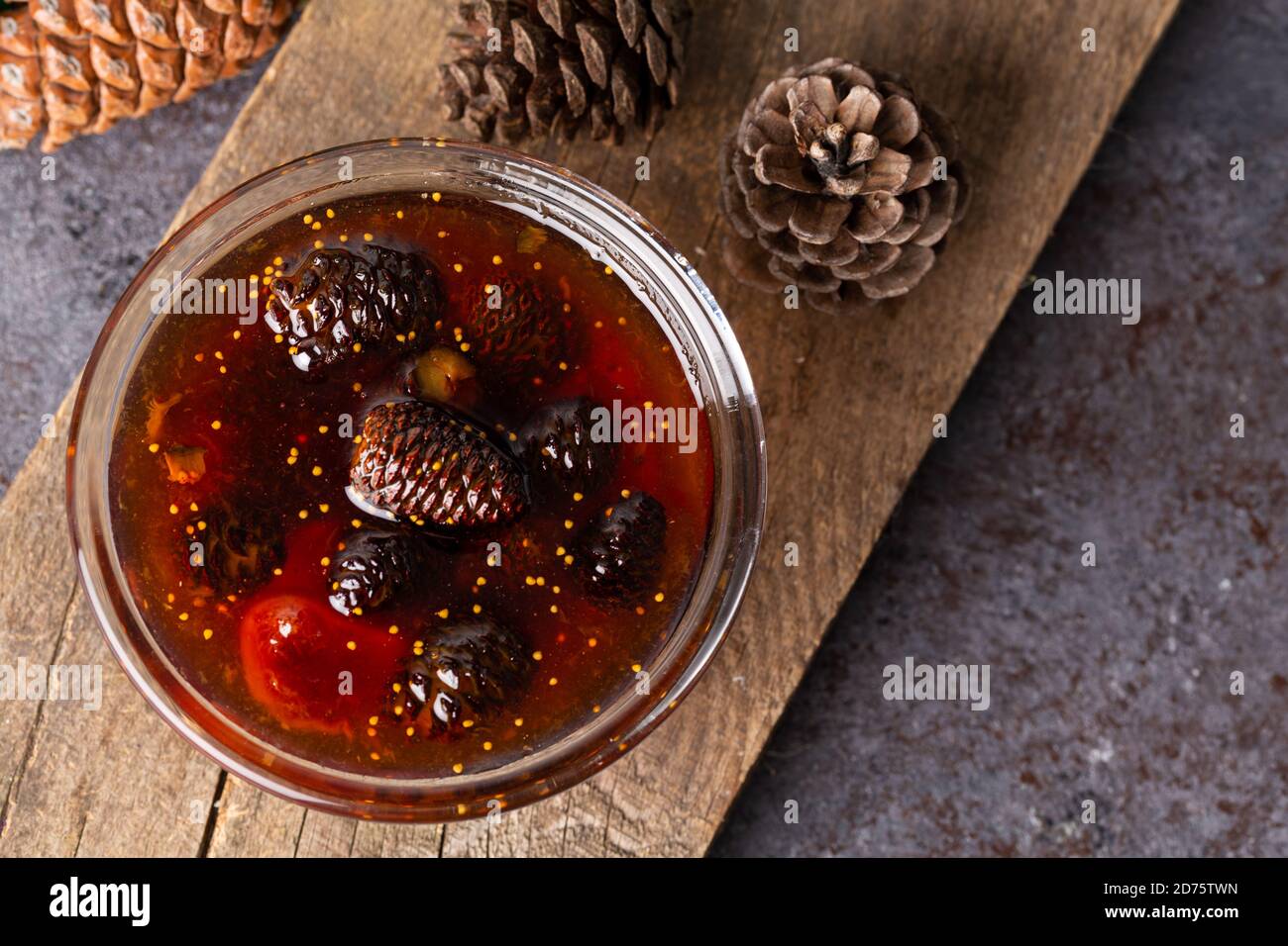 Young pine cones jam in glass bowl on wooden board. Delicious jam with ...