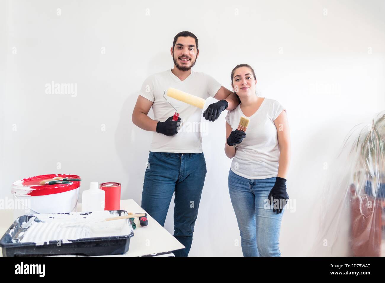 Young cheerful couple posing together while renovating their new house ... Young cheerful couple posing together while renovating their new house ...