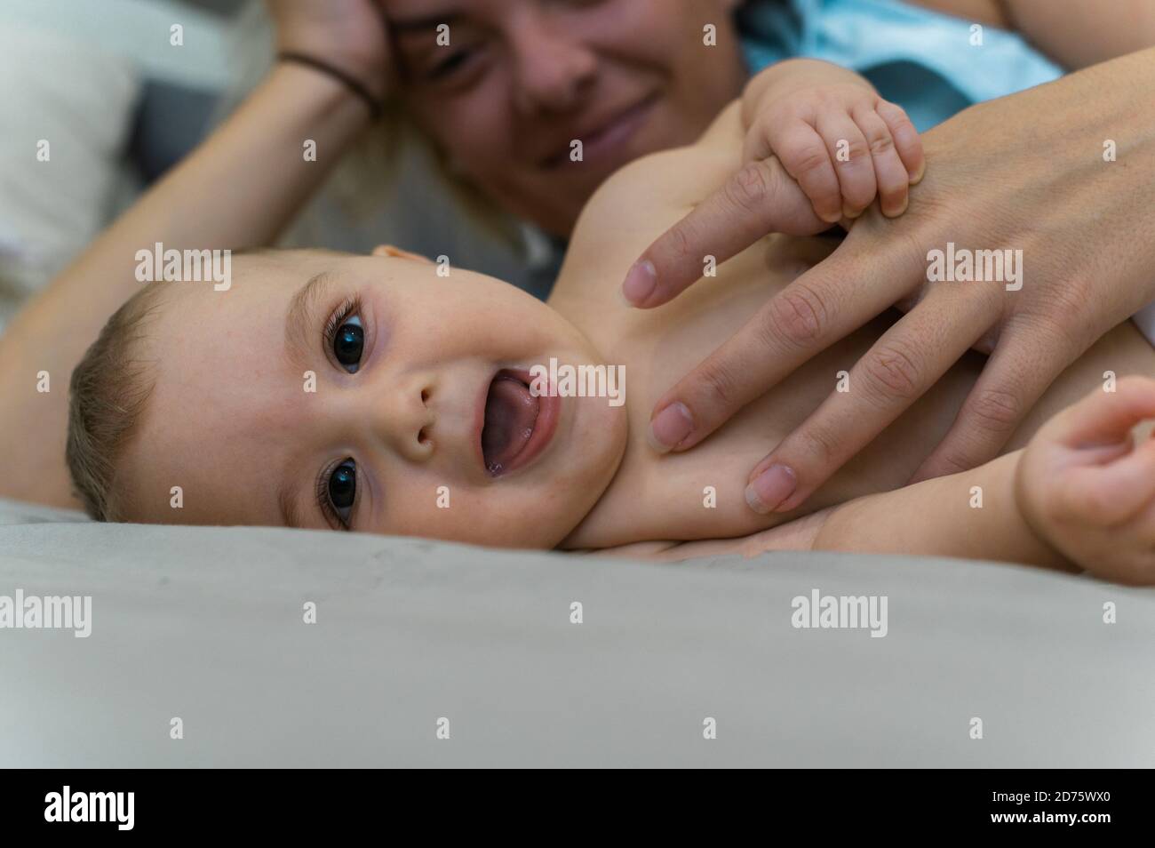 CLOSE-UP OF BABY LYING DOWN AND HIS MOTHER IS SEEN FROM BEHIND Stock ...