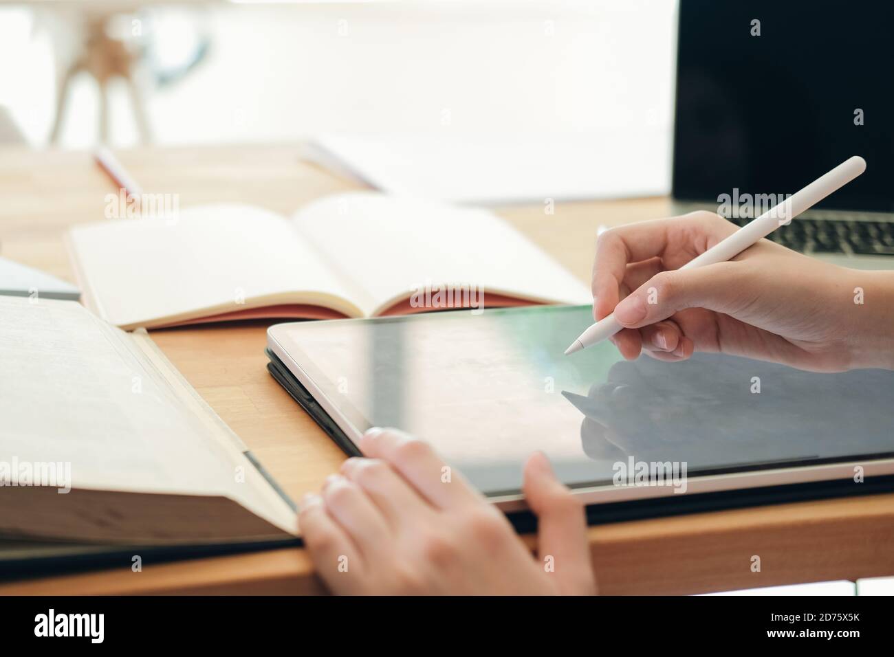 Young collage student using computer and digital tablet studying online ...