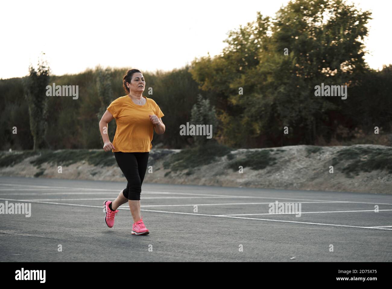 A middle-aged woman is jogging. running concept Stock Photo - Alamy