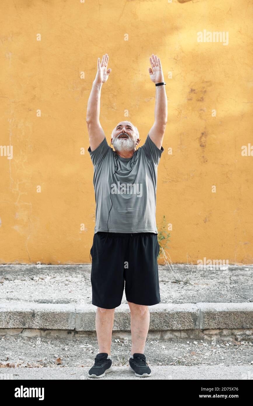 An overweight older man is stretching in front of a wall Stock Photo ...