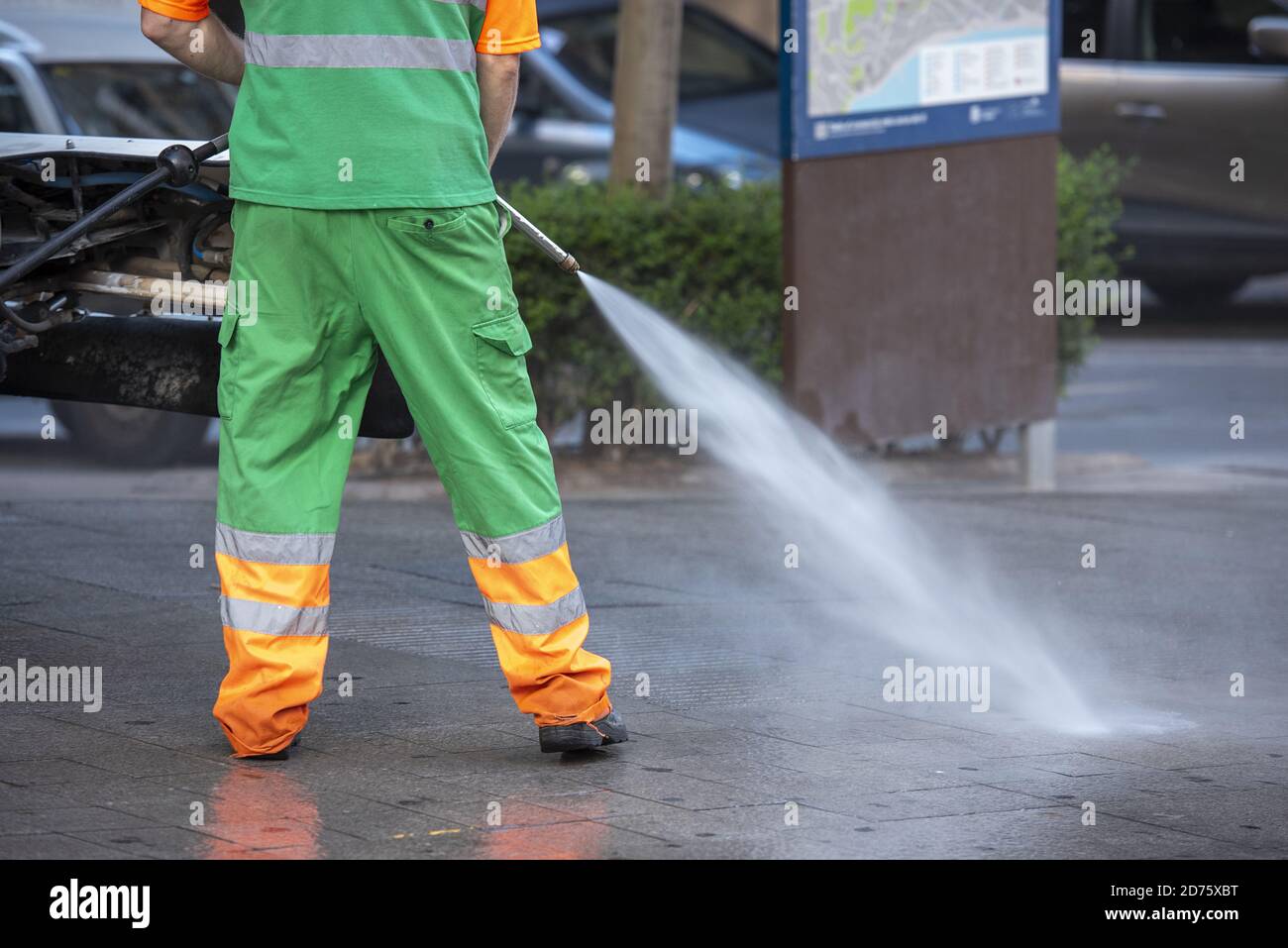 Maintenance worker cleaning up a park with a pressurized bleach water ...
