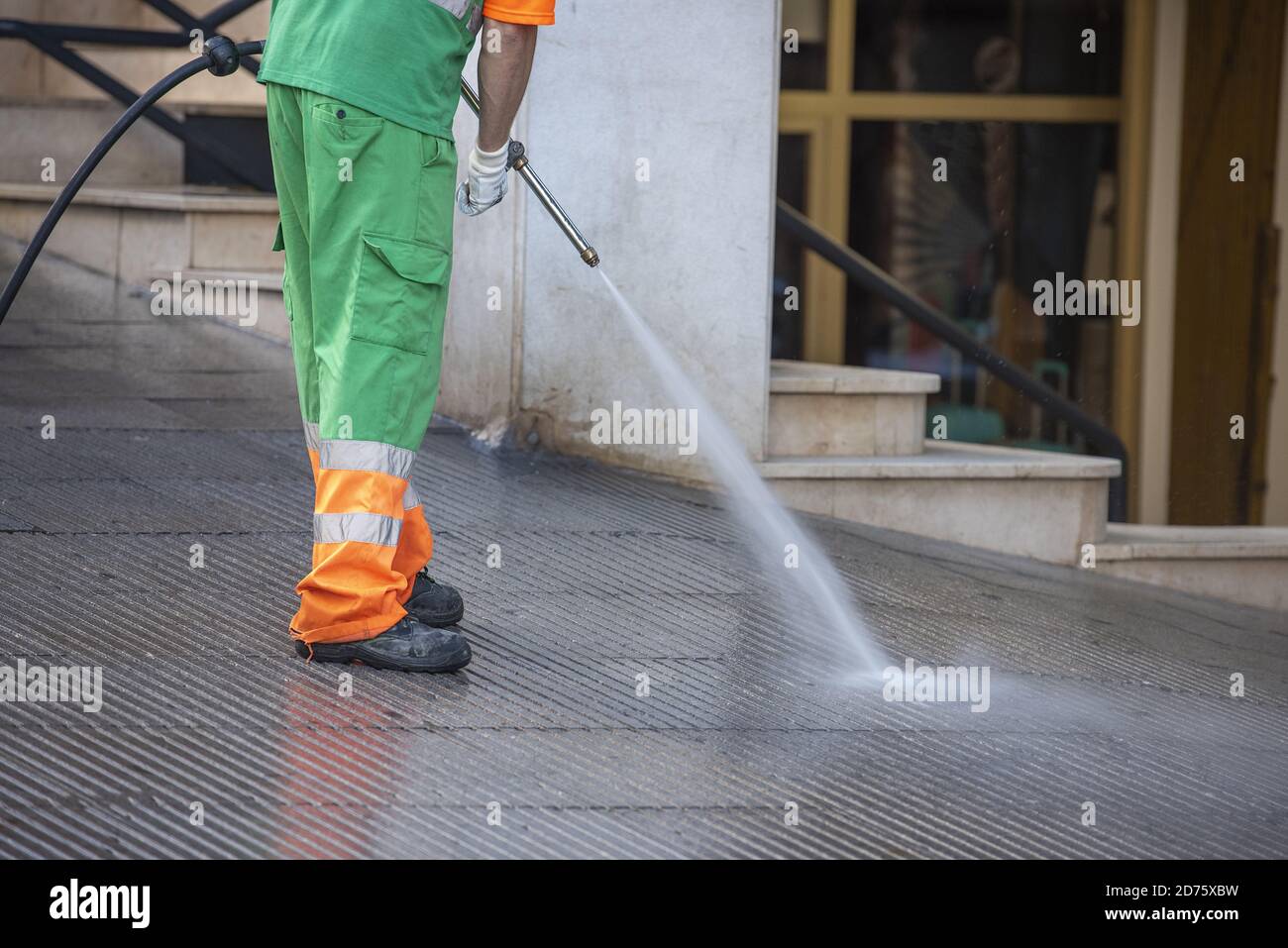 Maintenance worker cleaning up a park with a pressurized bleach water ...