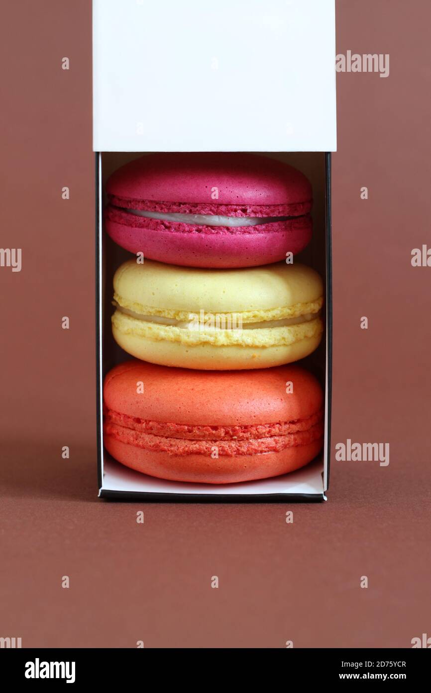 Multicolored macarons in a cardboard box with an open lid standing ...