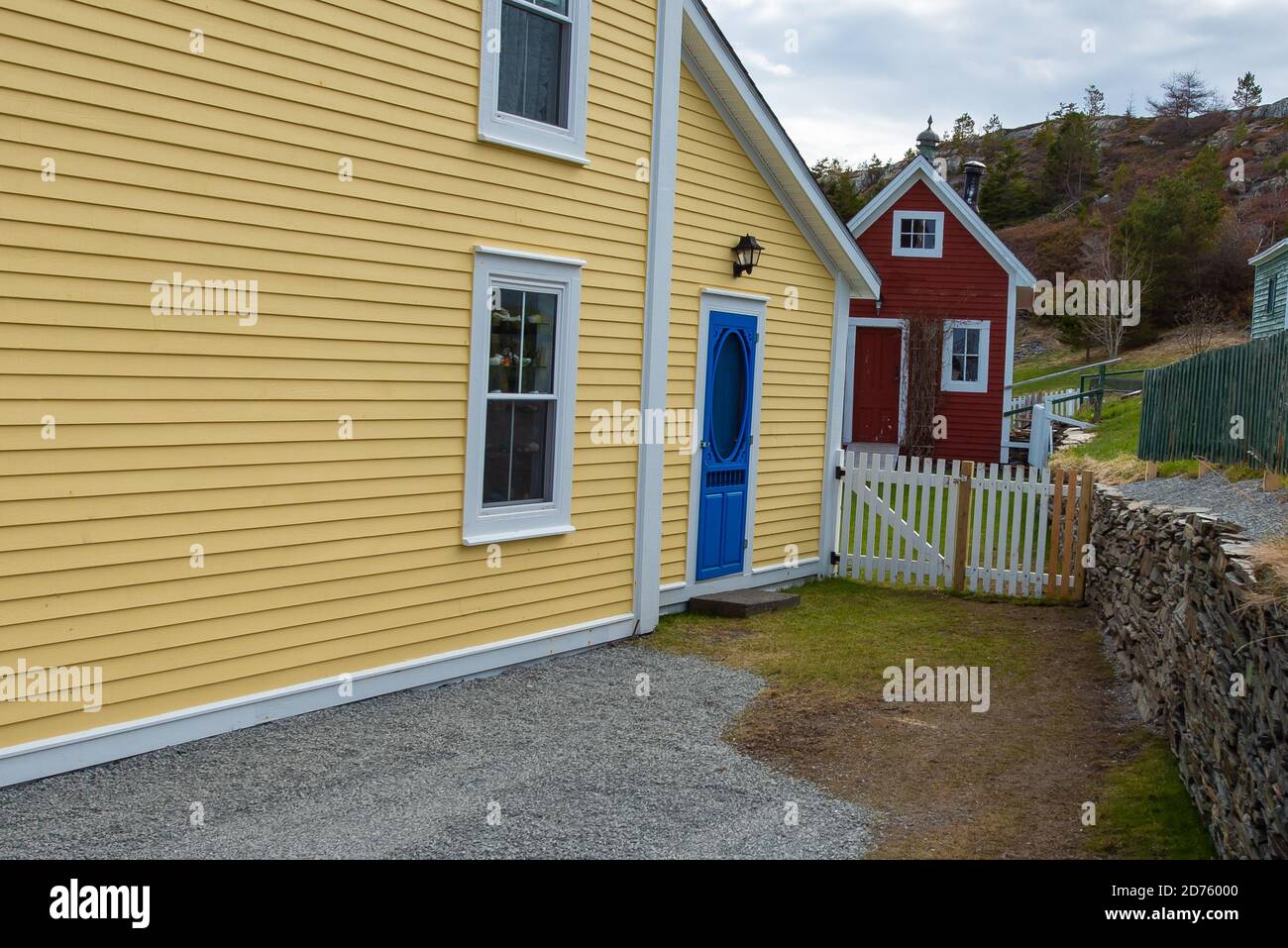 A bright blue cottage screen door on the exterior of a yellow building ...
