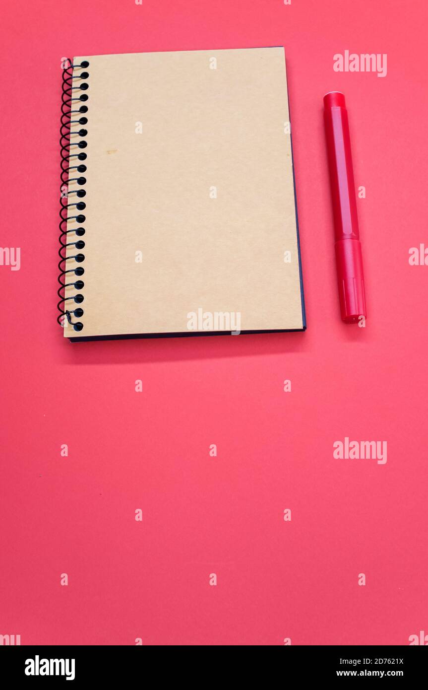 Vertical shot of a notebook and a red marker on a red surface Stock ...