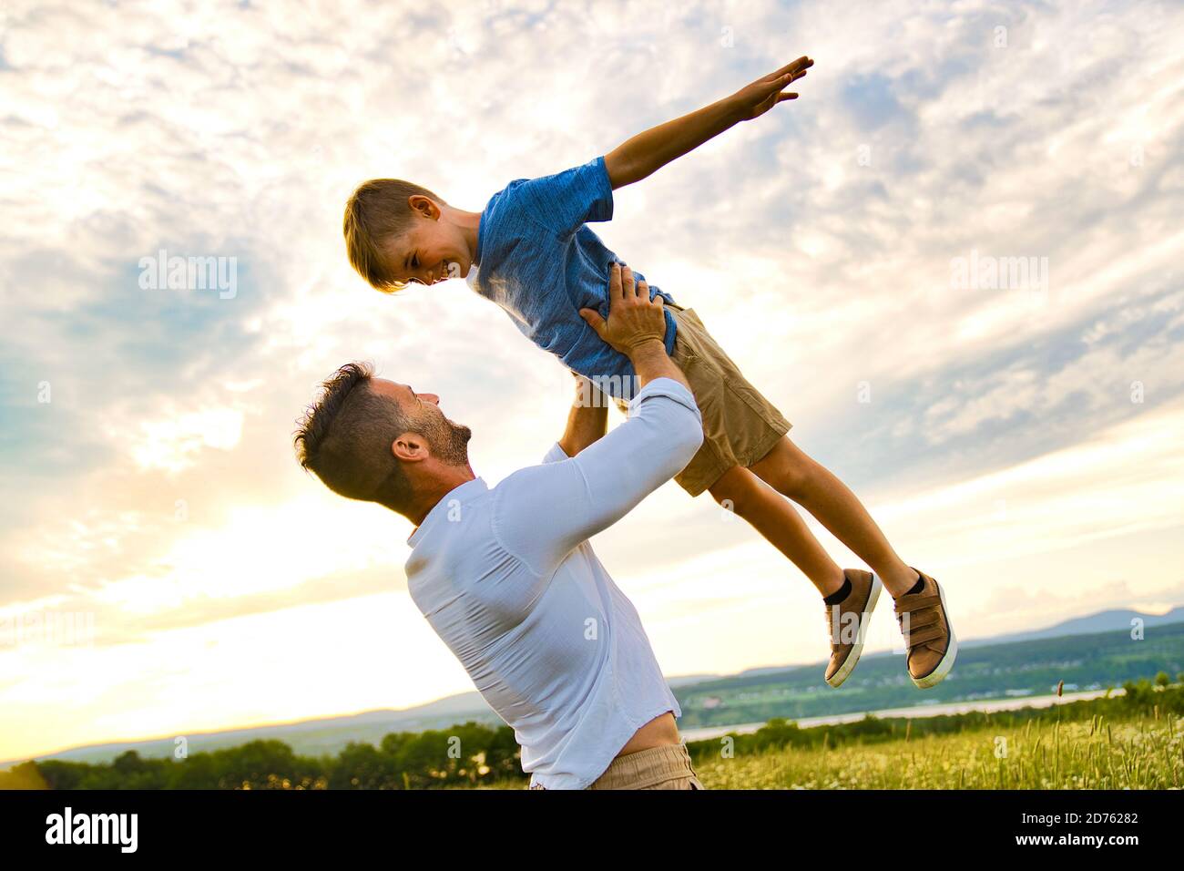 happy family of father and child on field at the sunset having fun ...
