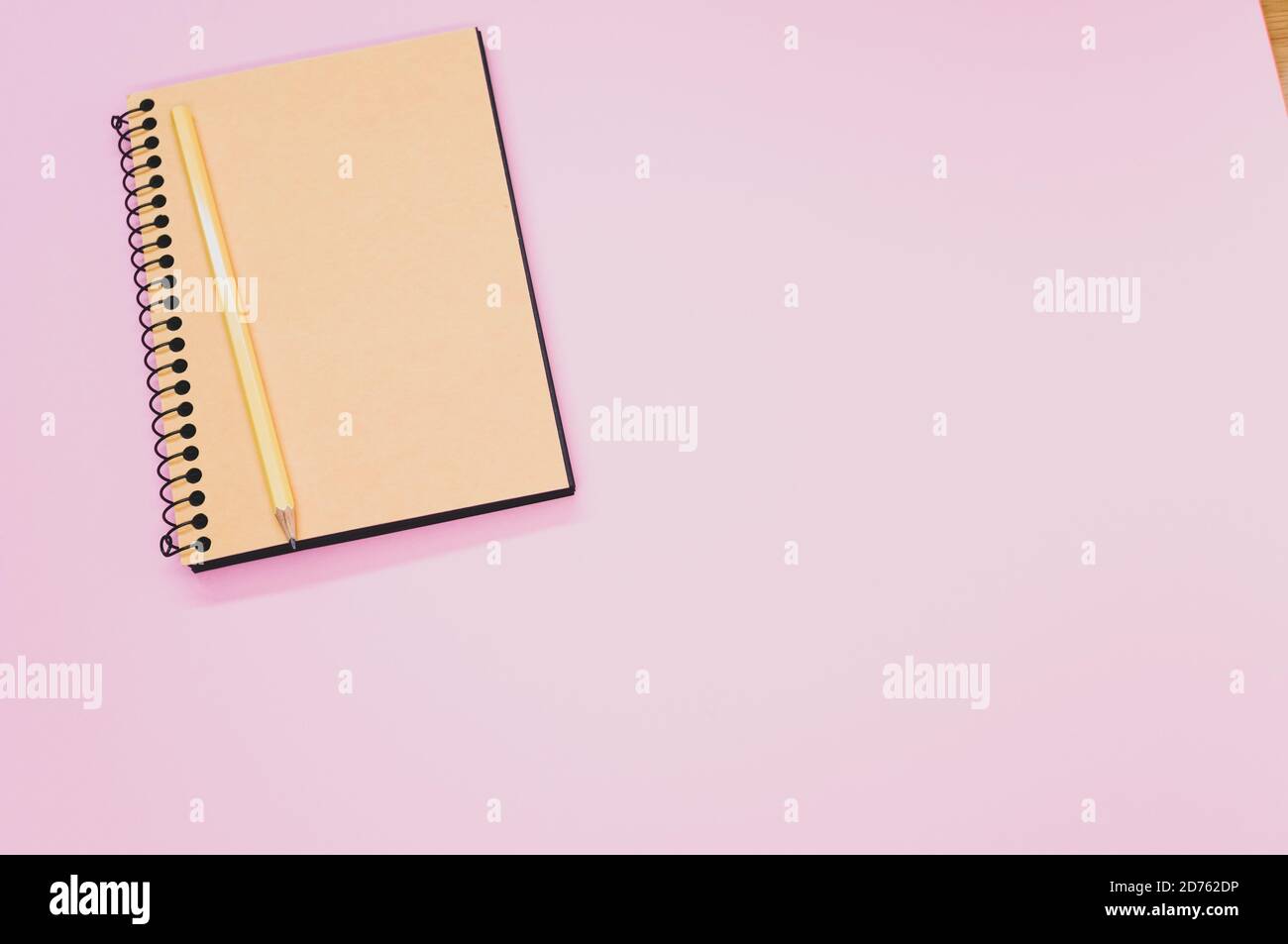 High angle shot of a notebook and a pencil on a pink surface Stock ...
