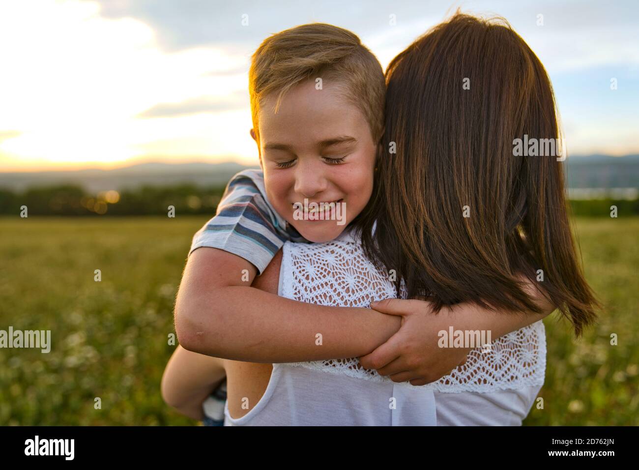 happy family of mother and child on field at the sunset having fun ...