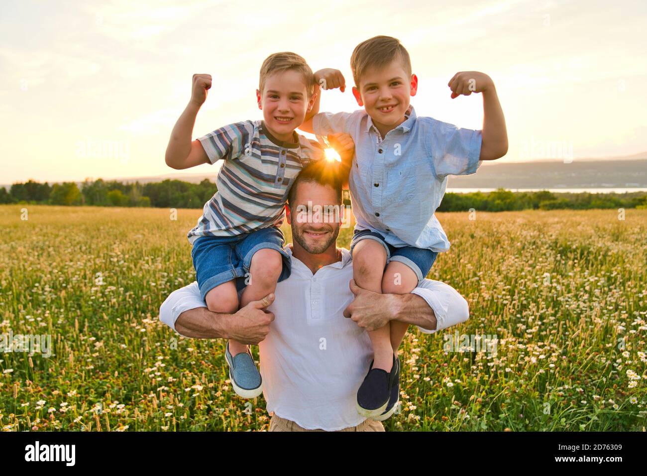 happy family of father and two childs on field at the sunset having fun ...