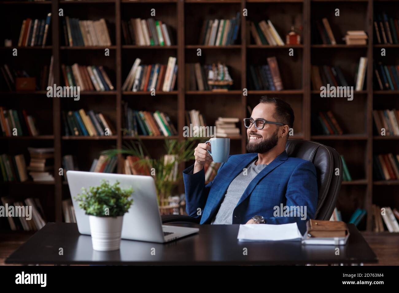 A young successful bearded businessman at his desk in the library ...