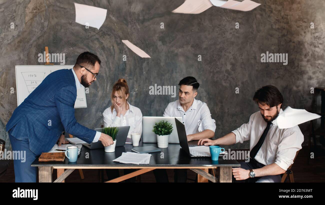 Angry boss reprimanding employee for bad work result sitting at ...