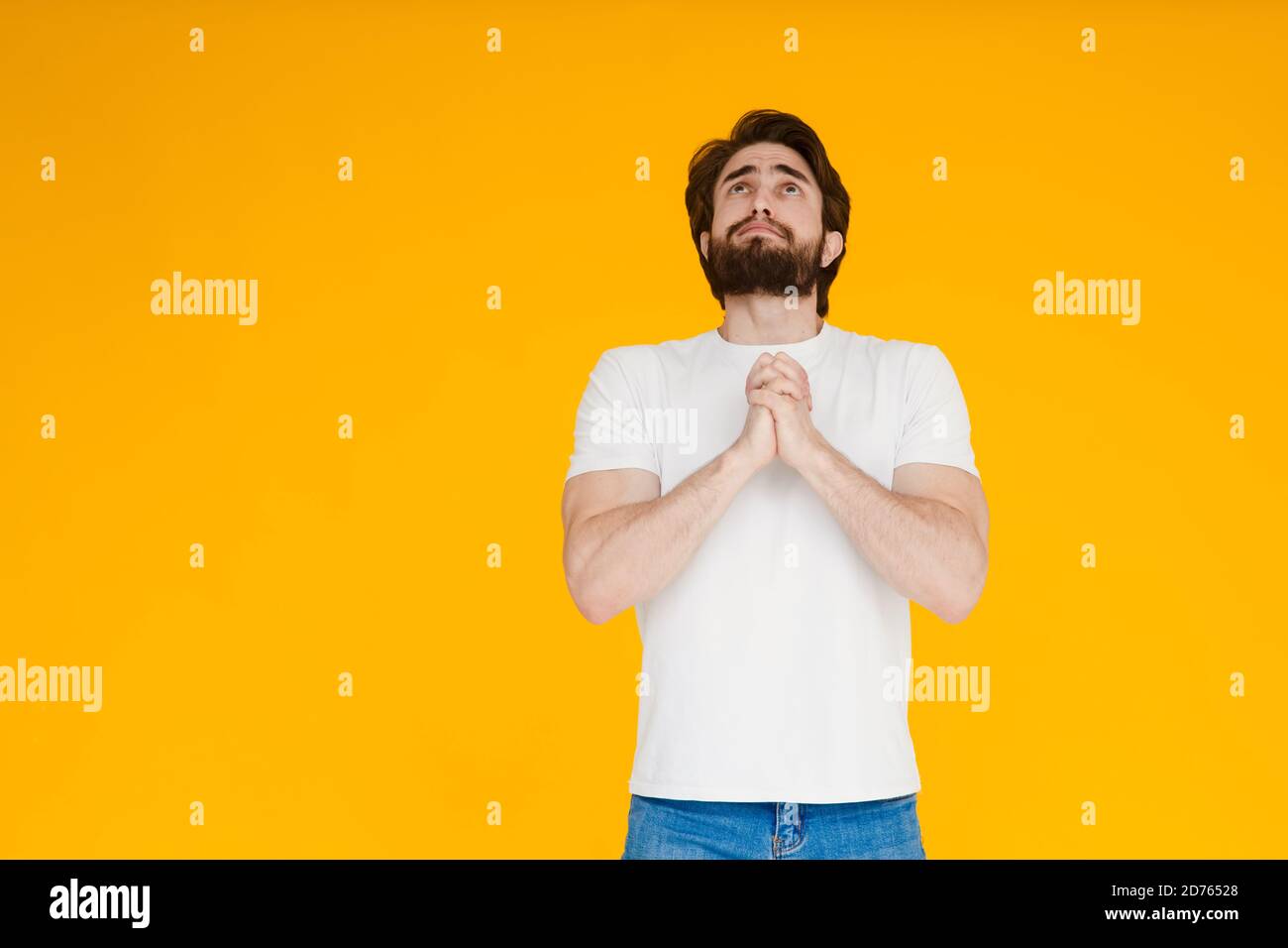 Pleading young bearded man guy in white casual t-shirt posing isolated ...
