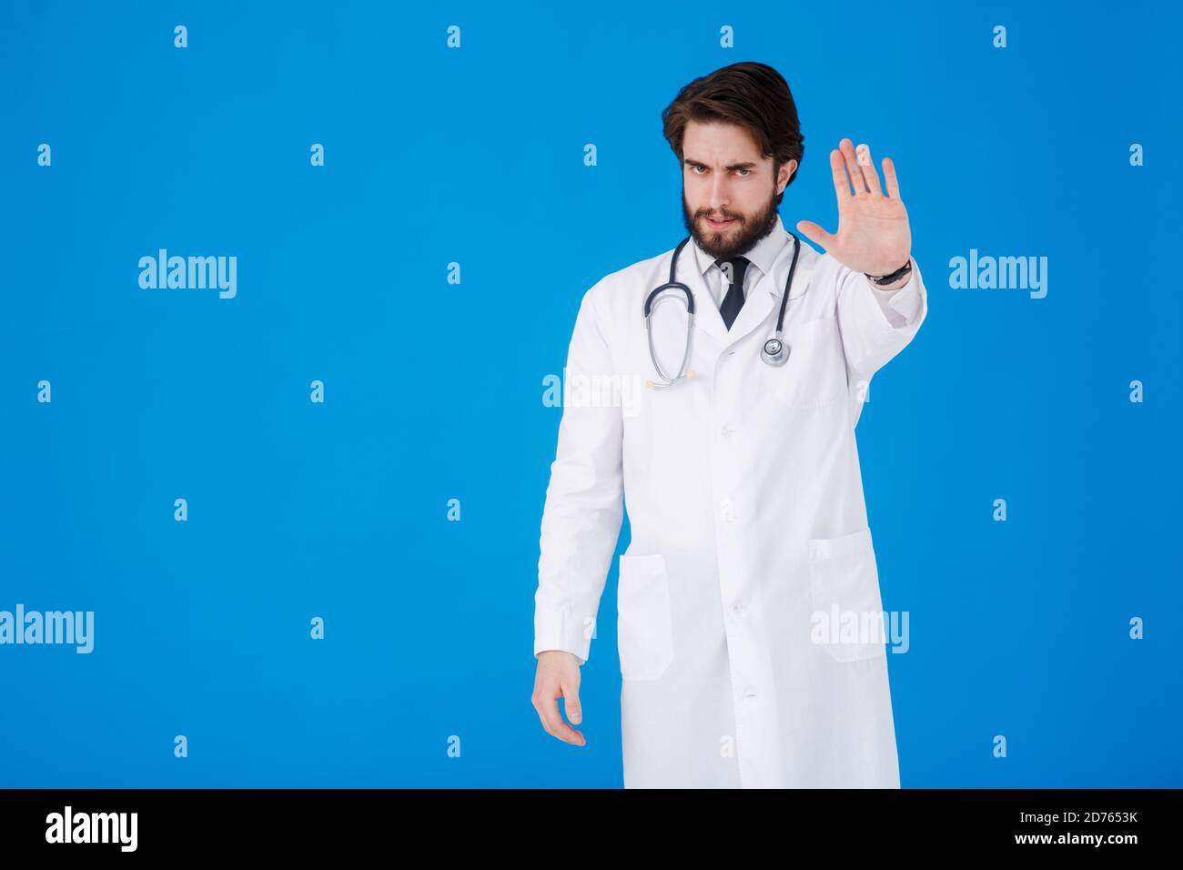 Portrait of serious doctor in professional medical white coat showing ...