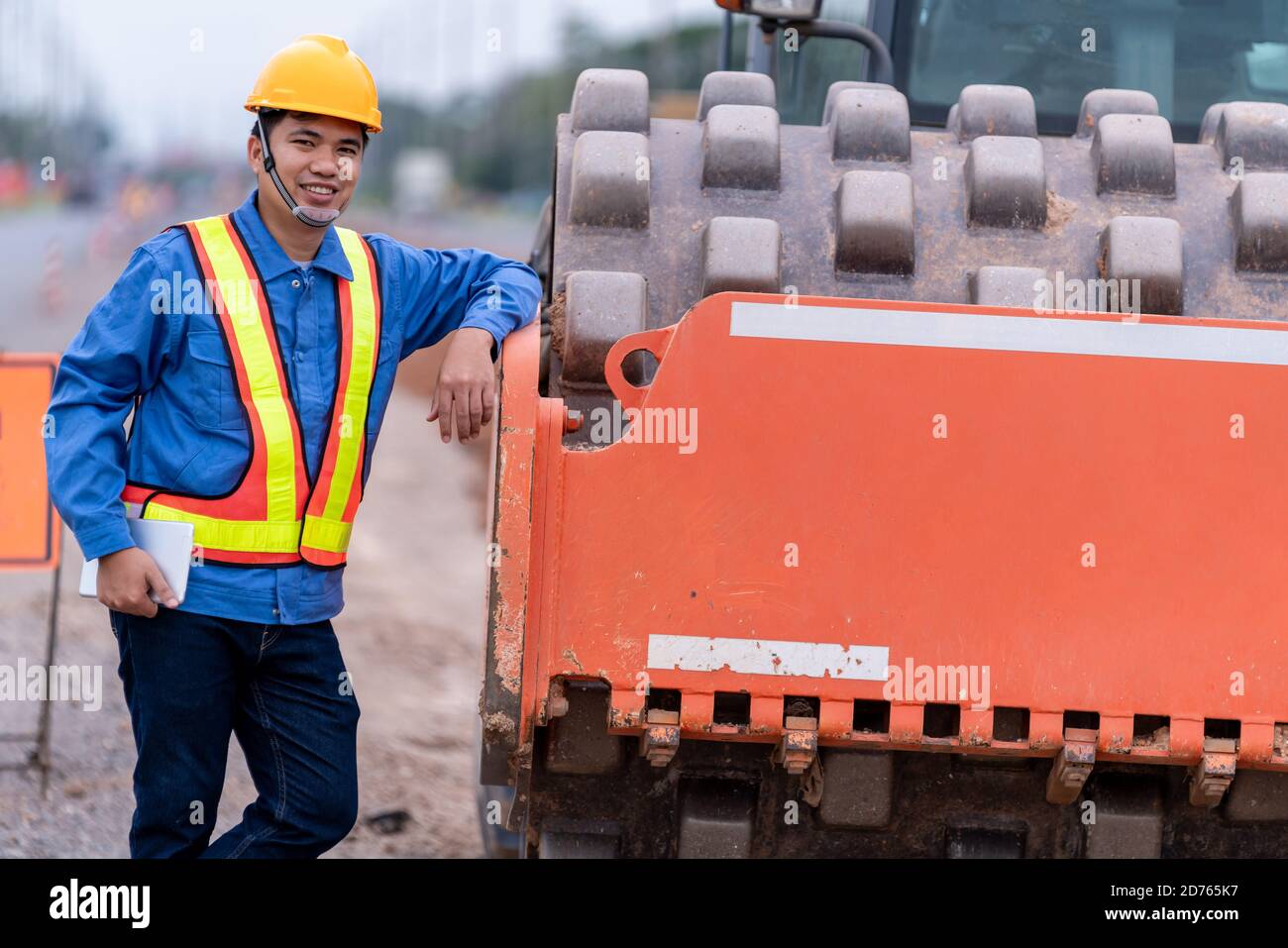 happy Civil engineer standing side yellow vibratory soil in road ...