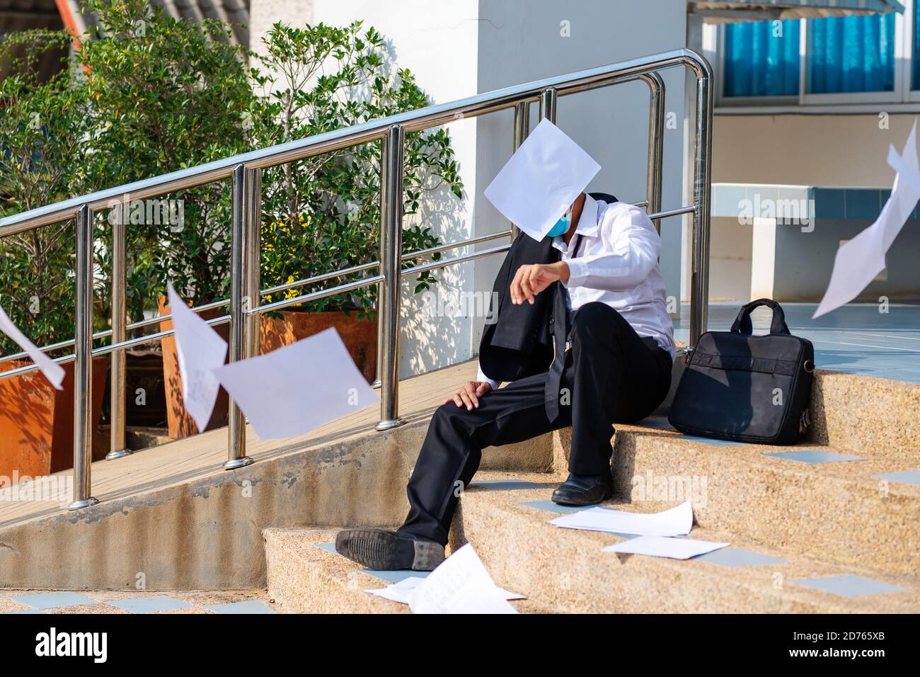 Asian businessman throw a job application and stress sitting on stair ...