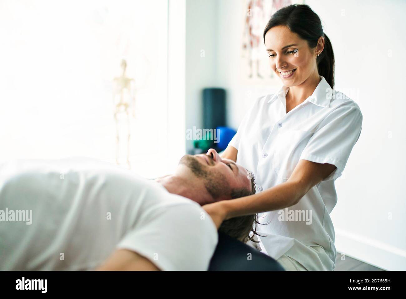 physiotherapist doing neck treatment with patient in bright office ...