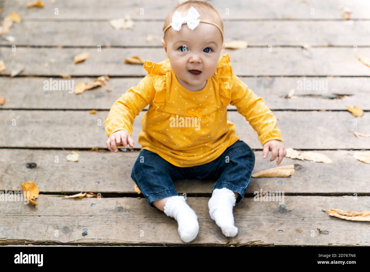 baby sit on bridge with maple fall leaves close Stock Photo - Alamy