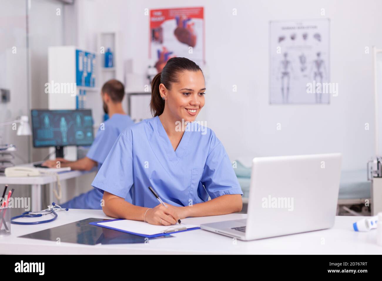Medical practitioner sitting at desk in hospital office using laptop ...