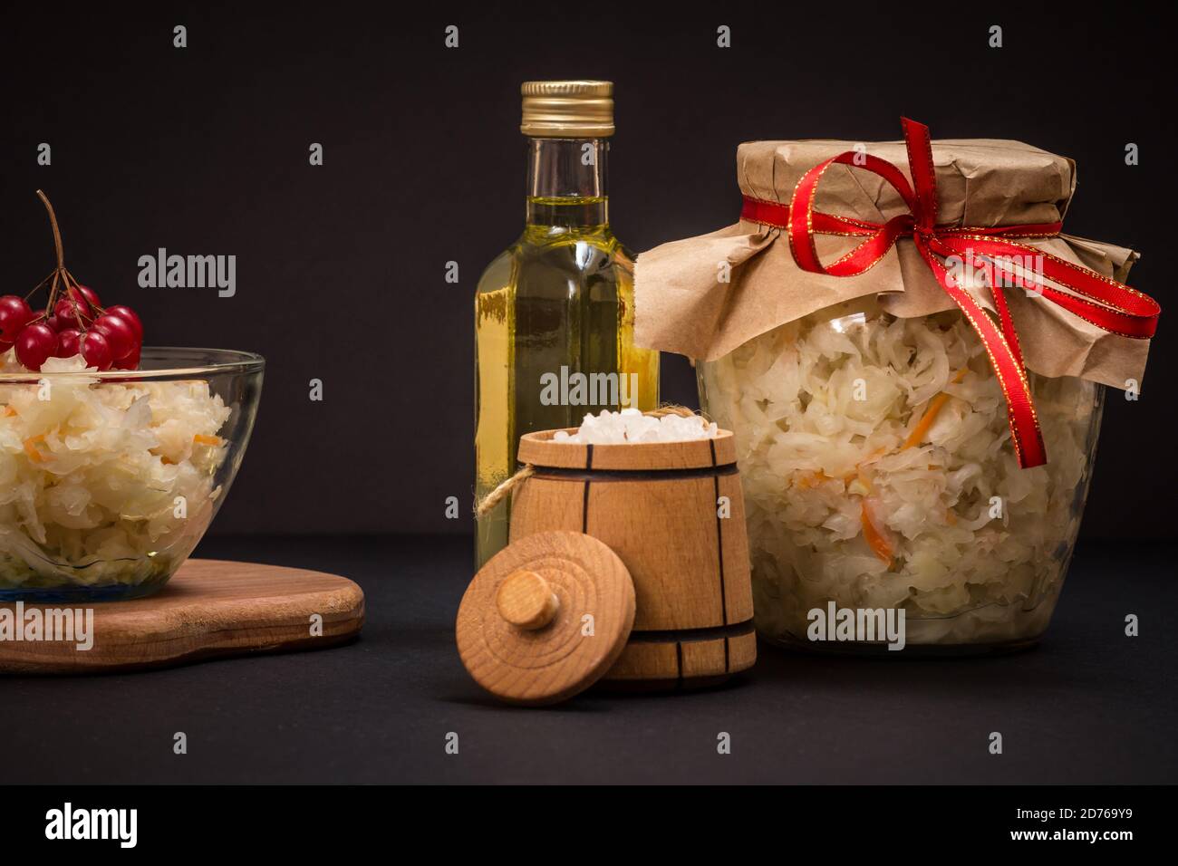 Homemade fermented cabbage in a glass bowl and a jar, a small wooden ...