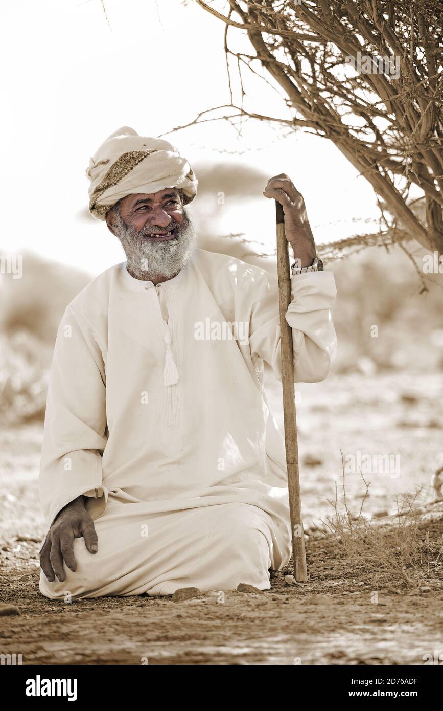 old Arab man siting in the Arabian desert on the ground talking Stock ...