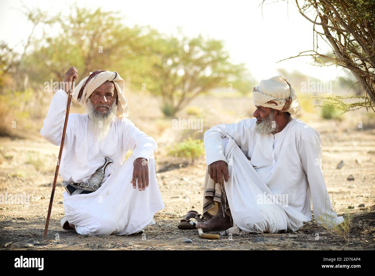 old Arab man siting in the Arabian desert on the ground talking Stock ...