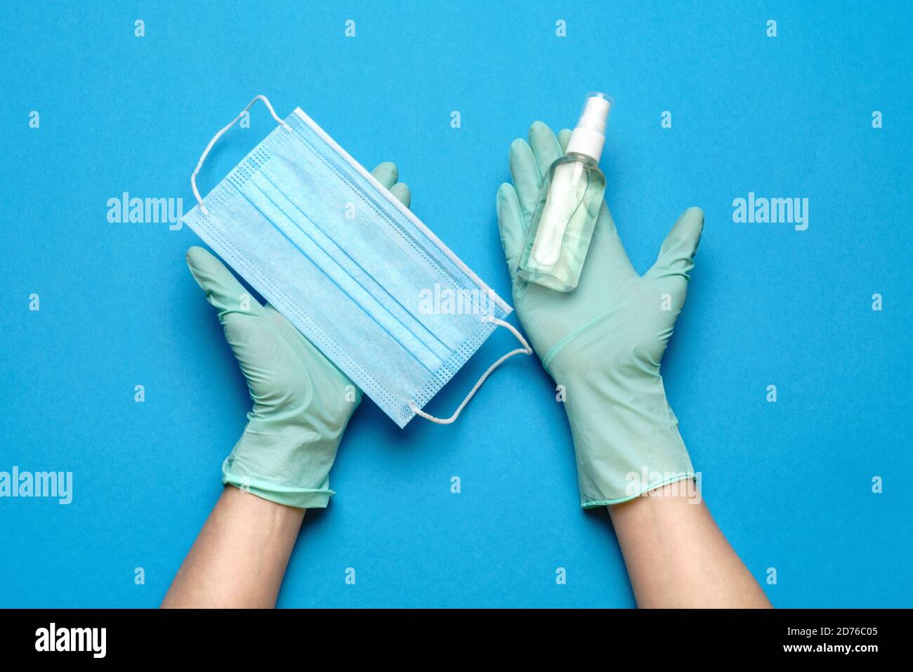 Human hand in protective glove holding face protective mask and alcohol ...