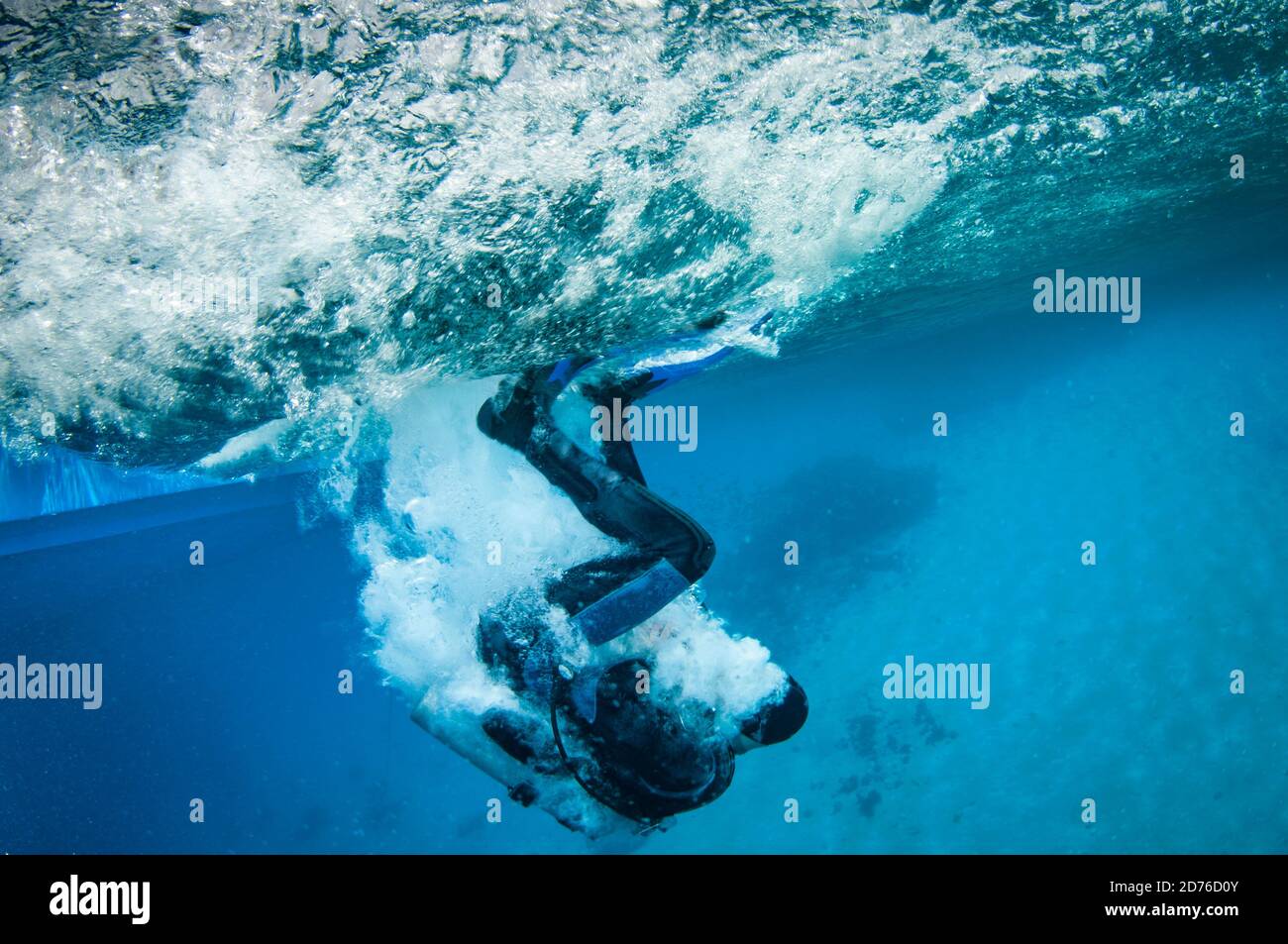 scuba diver enters the water from a boat and makes bubbles on the water ...