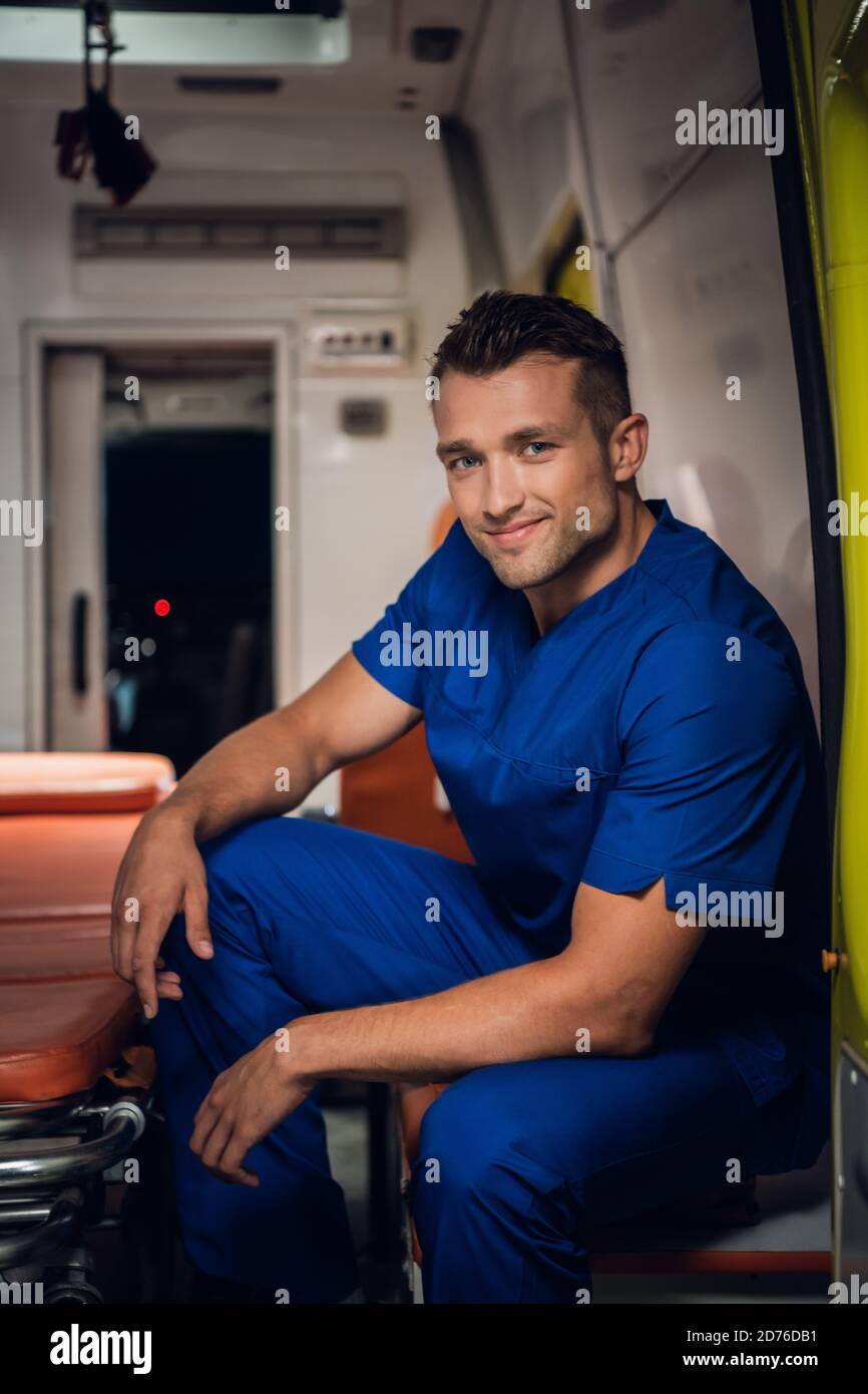 Portrait of a smiling young man in a medical uniform sitting in an ...