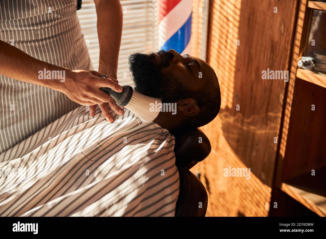 Barber brushing off hair around client neckline after beard trimming ...