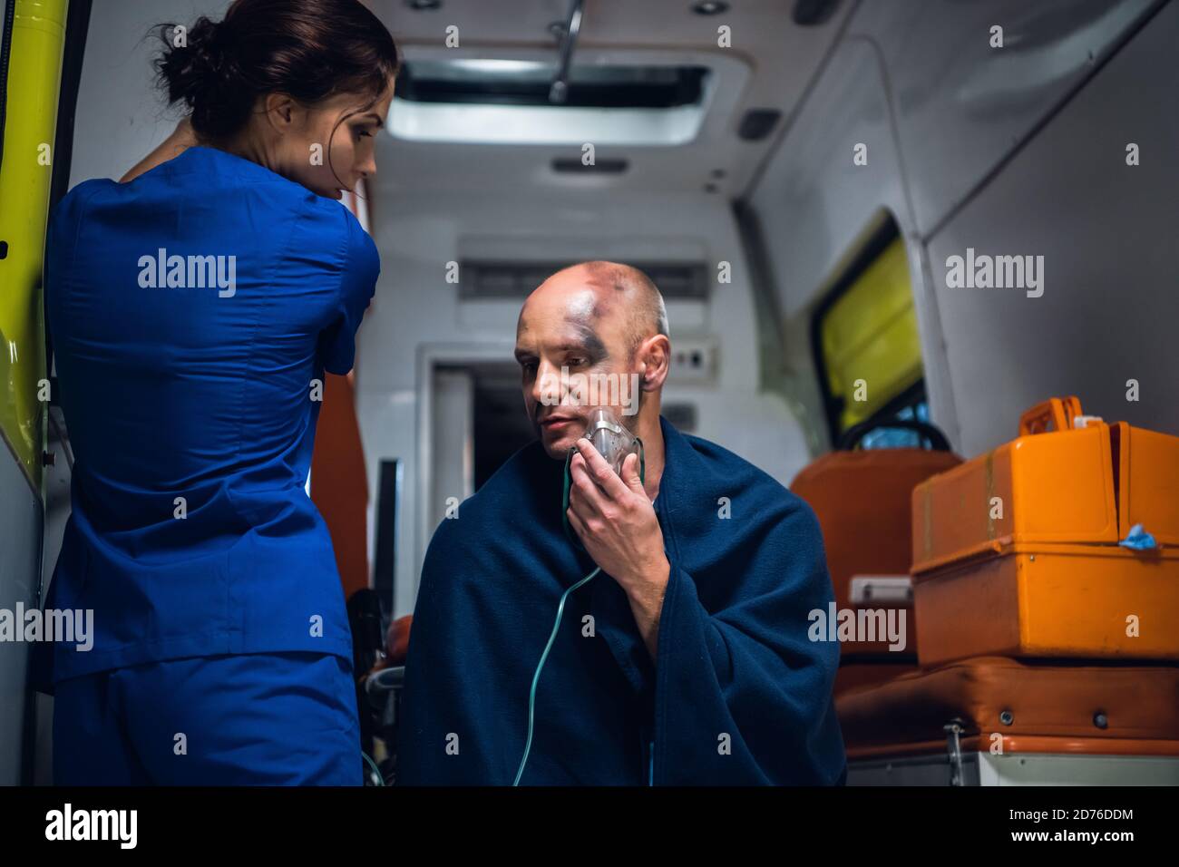 A paramedic in a uniform talking to an injured man who takes off his ...