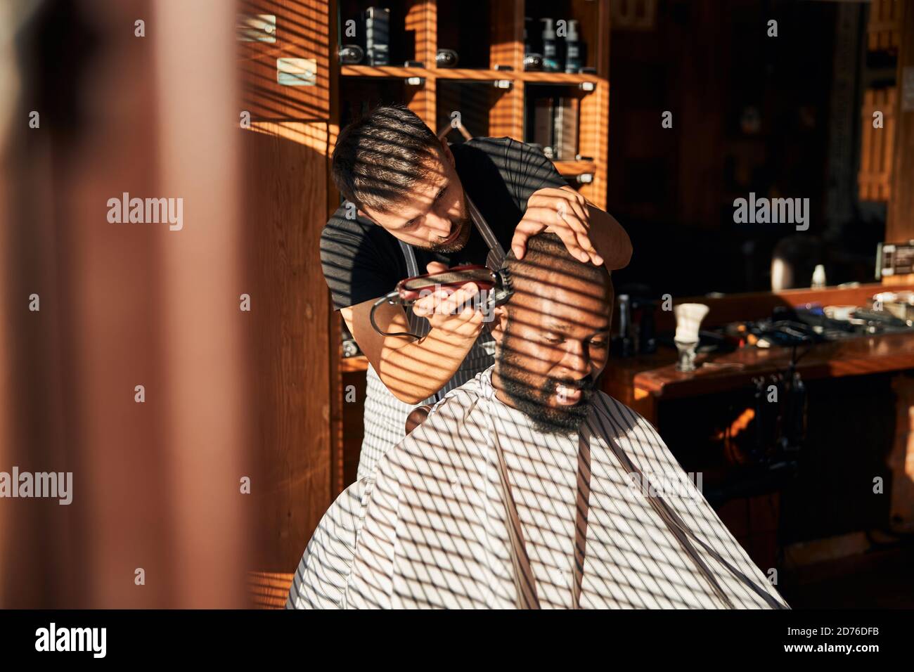 Barber cutting client hair with professional electric hair clipper ...