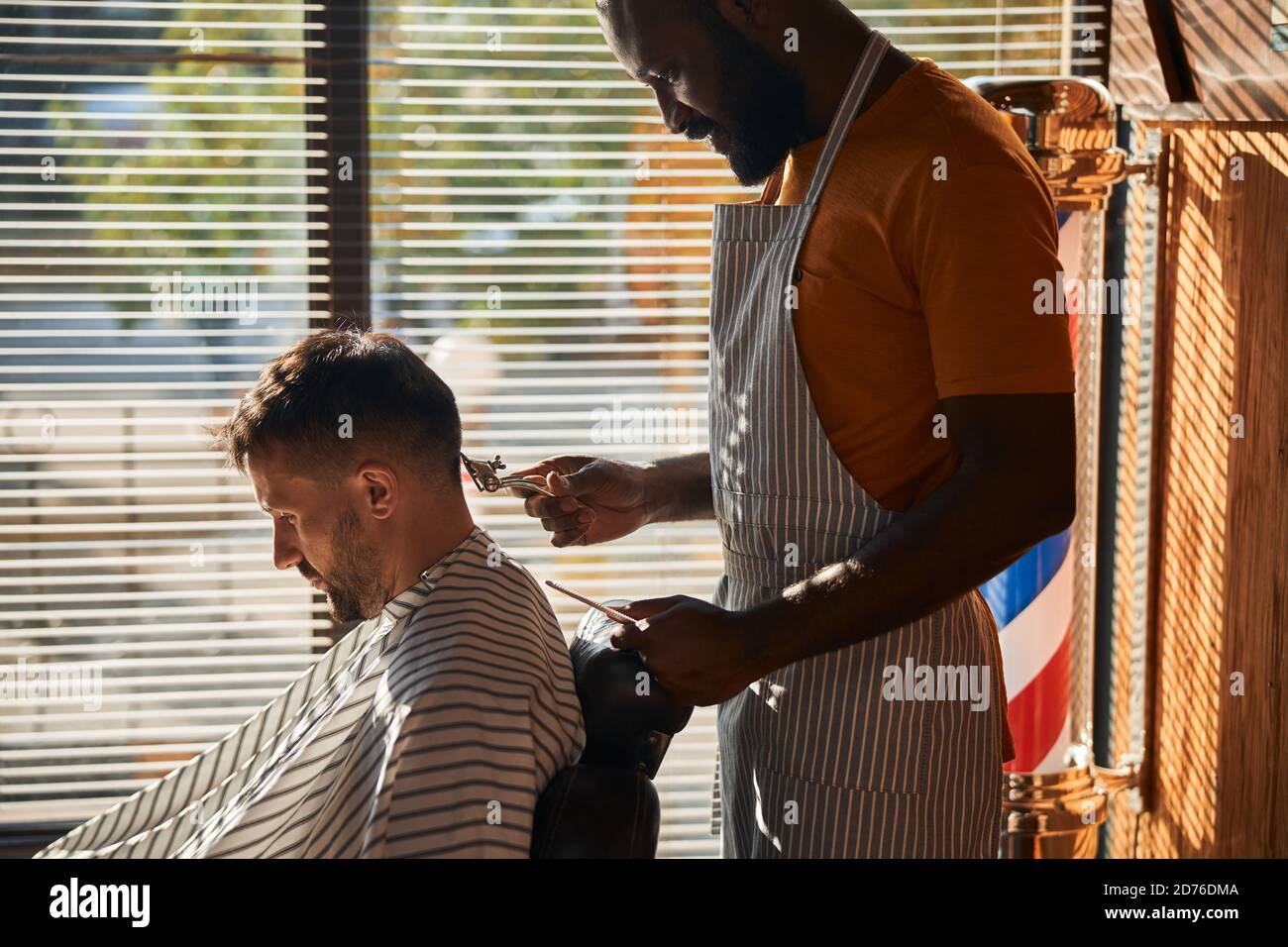 Handsome male barber cutting client hair with metal hair clipper Stock ...