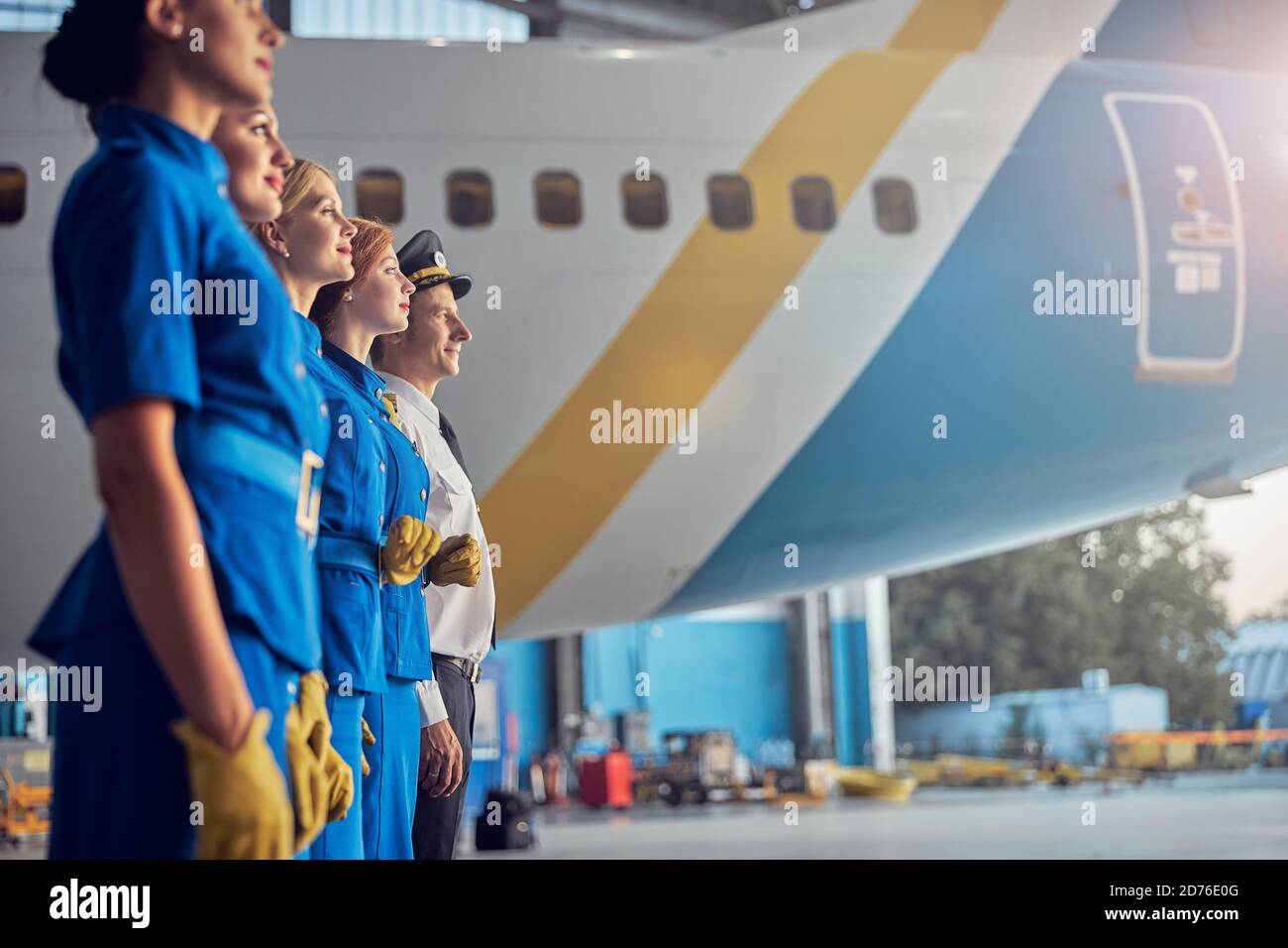Happy smiling pilot and charming stewardesses looking ahead in the ...