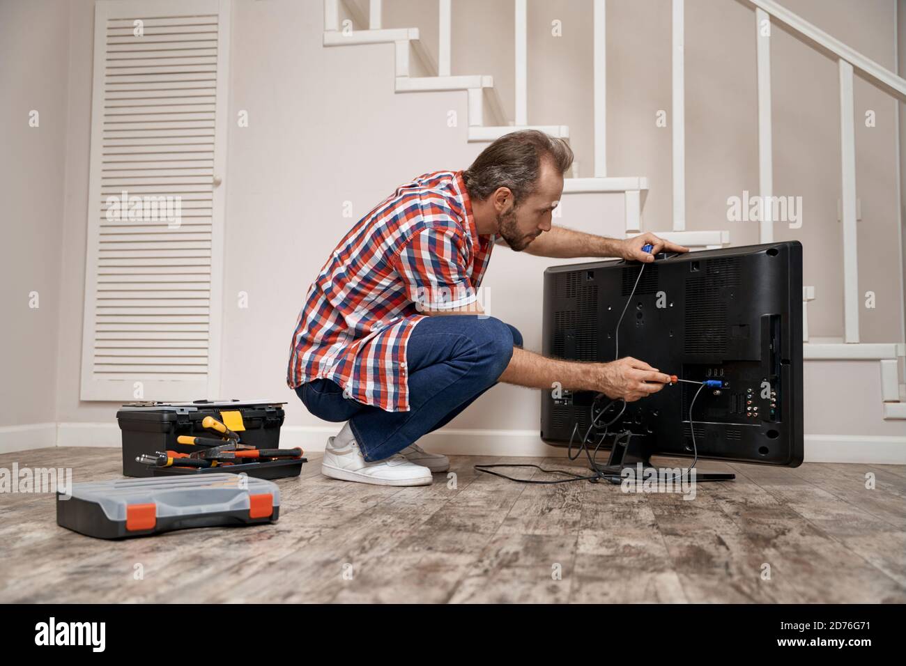 Young caucasian service man fixing tv set Stock Photo - Alamy