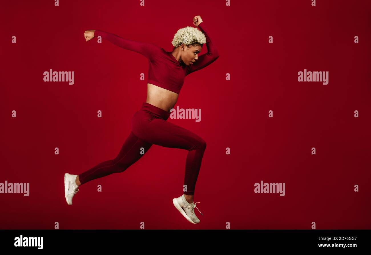 Female african american athlete sprinting against maroon background ...