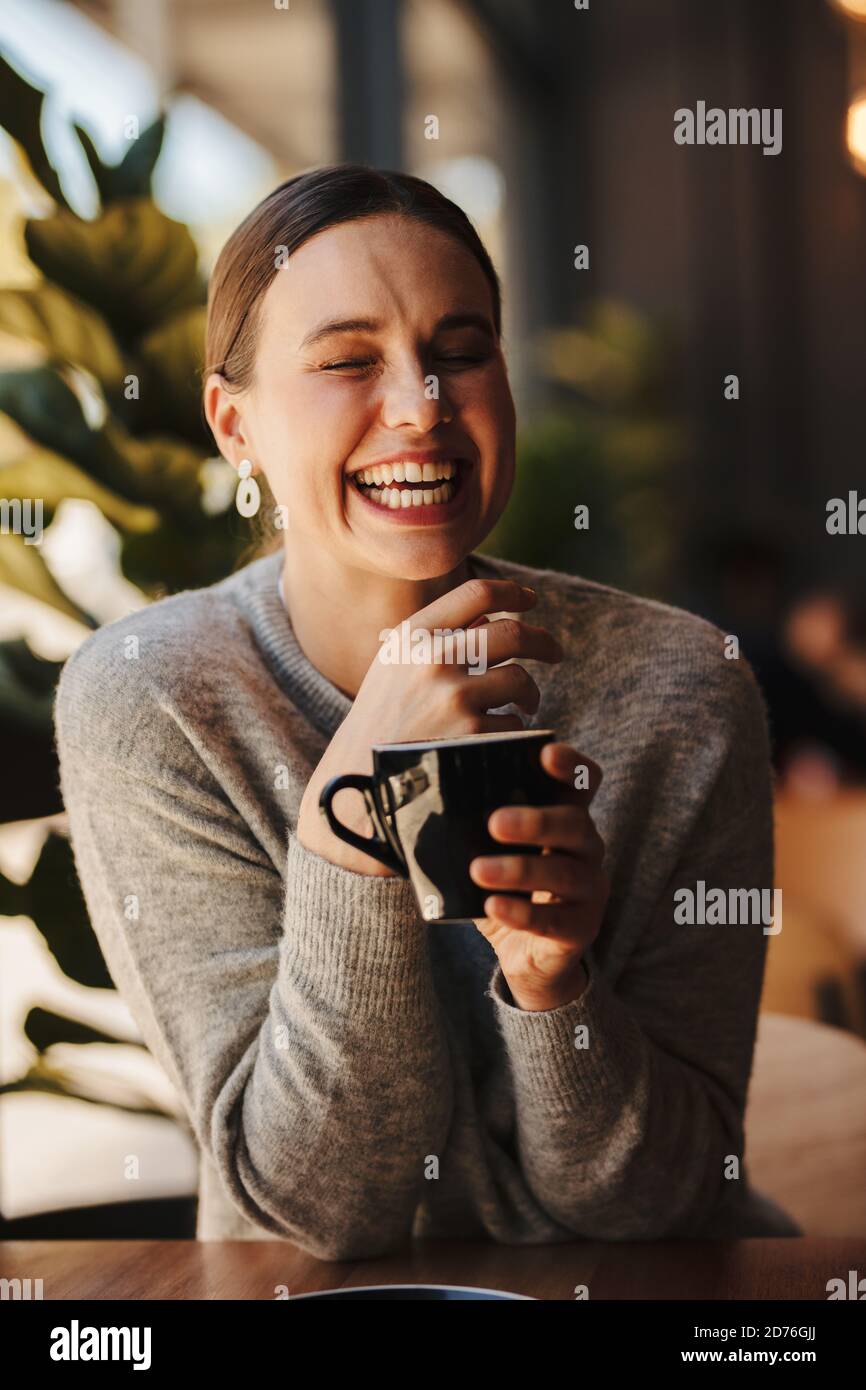 Pretty woman at a coffee shop. Female drinking coffee and laughing at ...