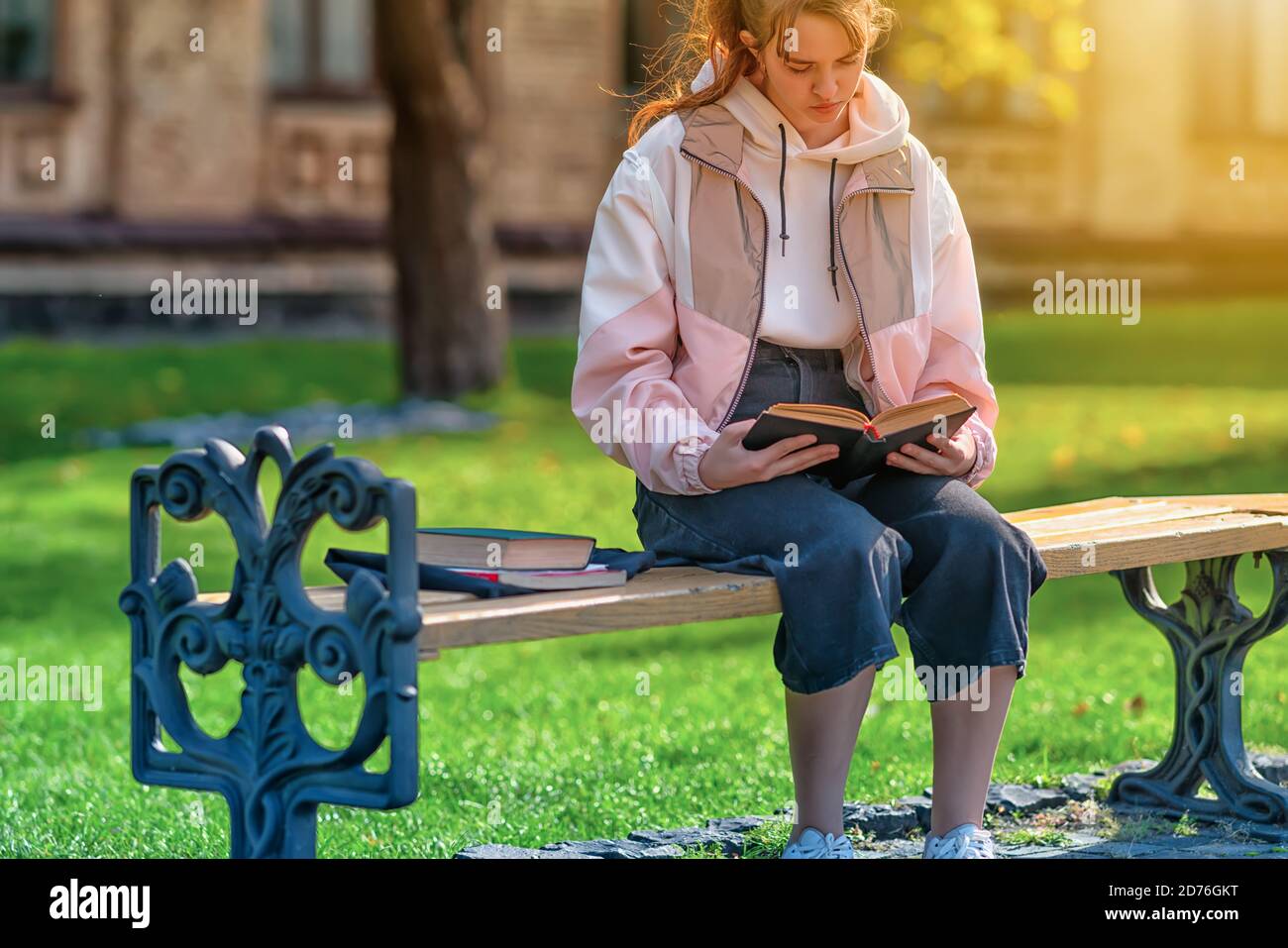 Close up on a young girl reading a book in a park relaxing in the warm ...