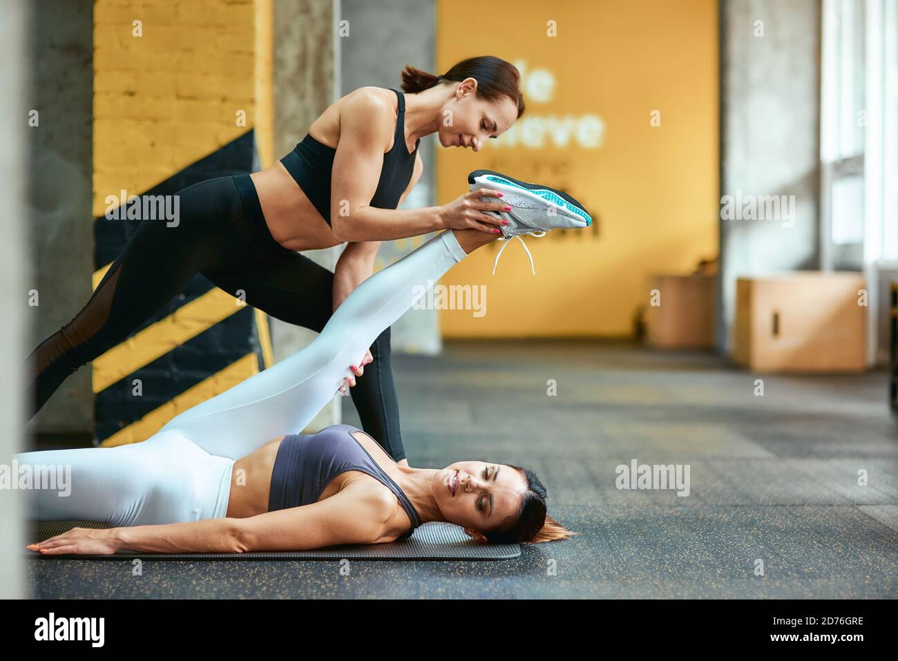 Flexible body. Young beautiful caucasian woman lying on yoga mat at gym ...
